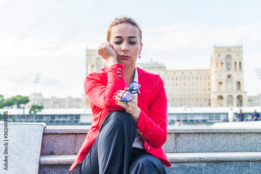 sad woman in a business suit sits on the steps. a business woman has ...