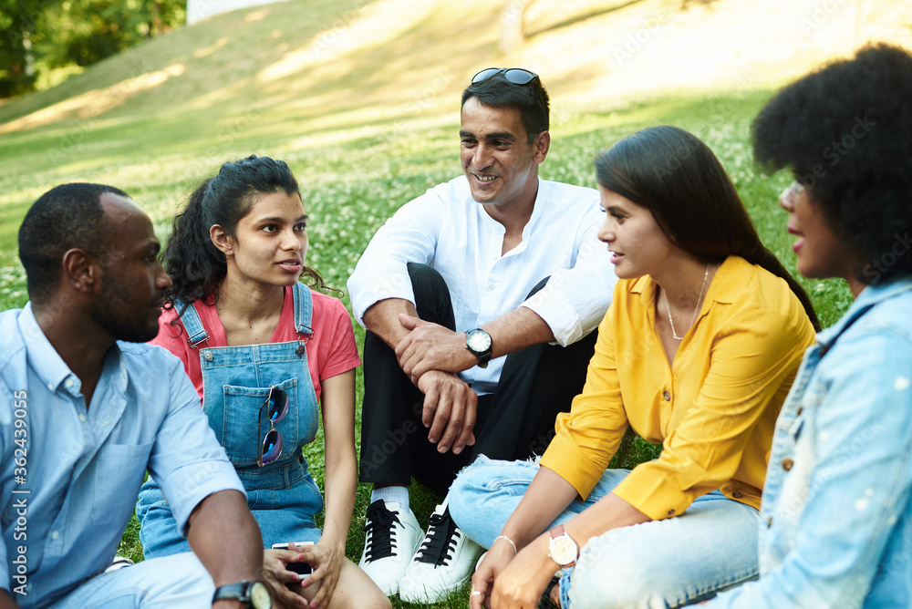 Afghan, black, mexican and indian chatting while sitting in the park on ...