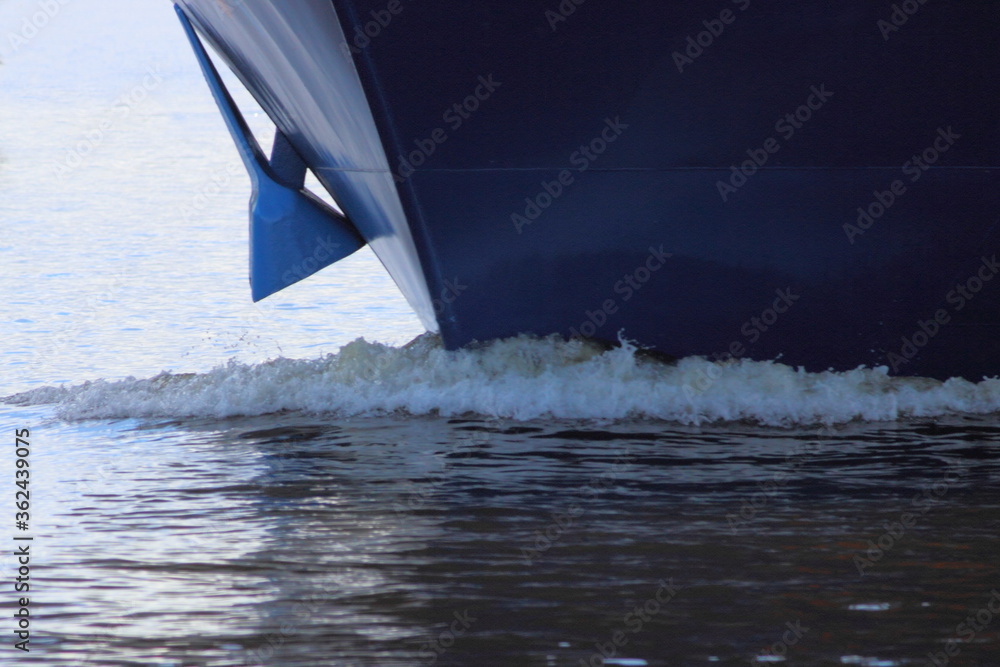 Bow keel wave and shipboard with anchor of blue commercial ship close ...