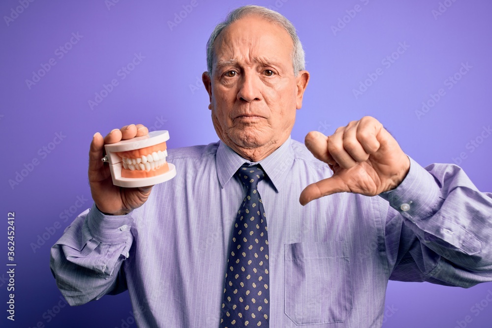 Grey haired senior man holding orthodontic prosthesis denture over ...