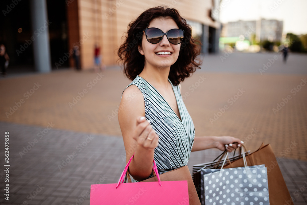 Young beautiful woman shopaholic walks out the shopping center with a ...
