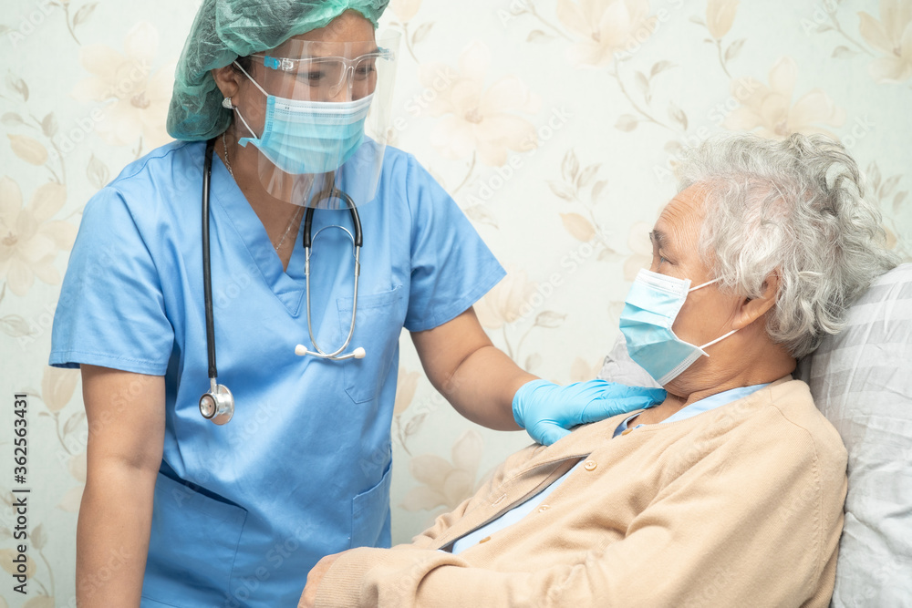 Asian doctor wearing face shield and PPE suit to check patient protect ...