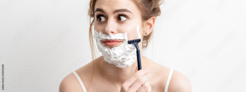Beautiful young caucasian woman shaving her face by razor on white ...