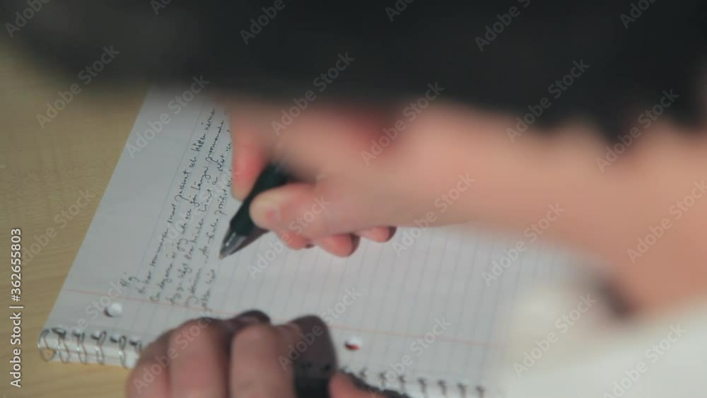 Person writing letter on ruled notebook paper in spiral binder with pen ...