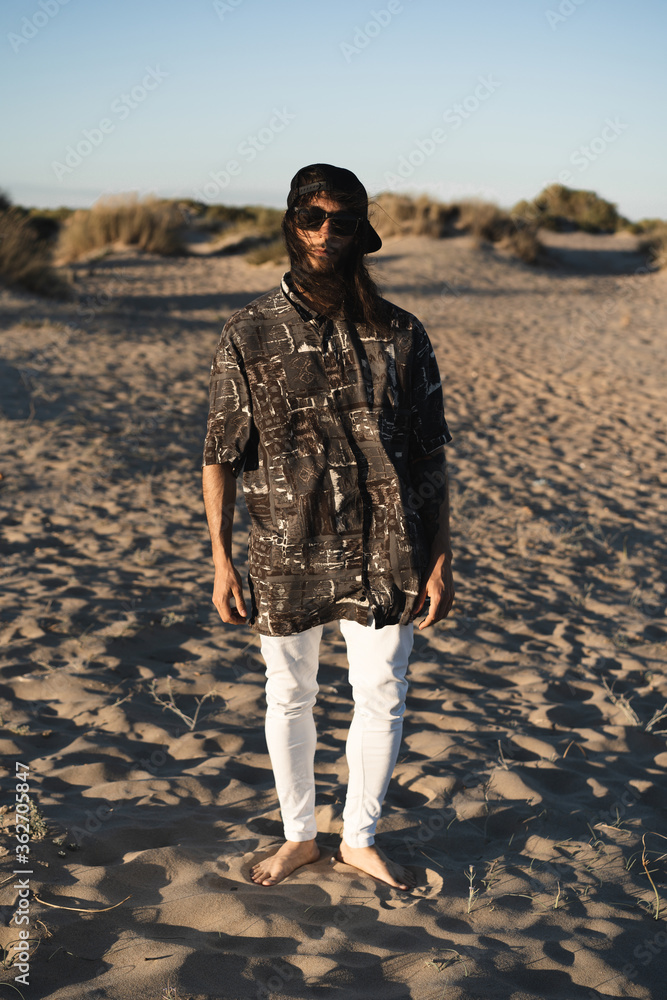 Modelo de estilo surfero con pelo largo, gafas de sol y gorra, en unas ...
