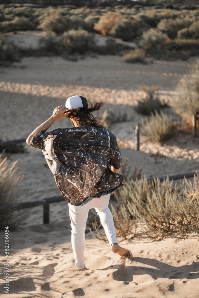 Modelo de estilo surfero con pelo largo, gafas de sol y gorra, en unas ...