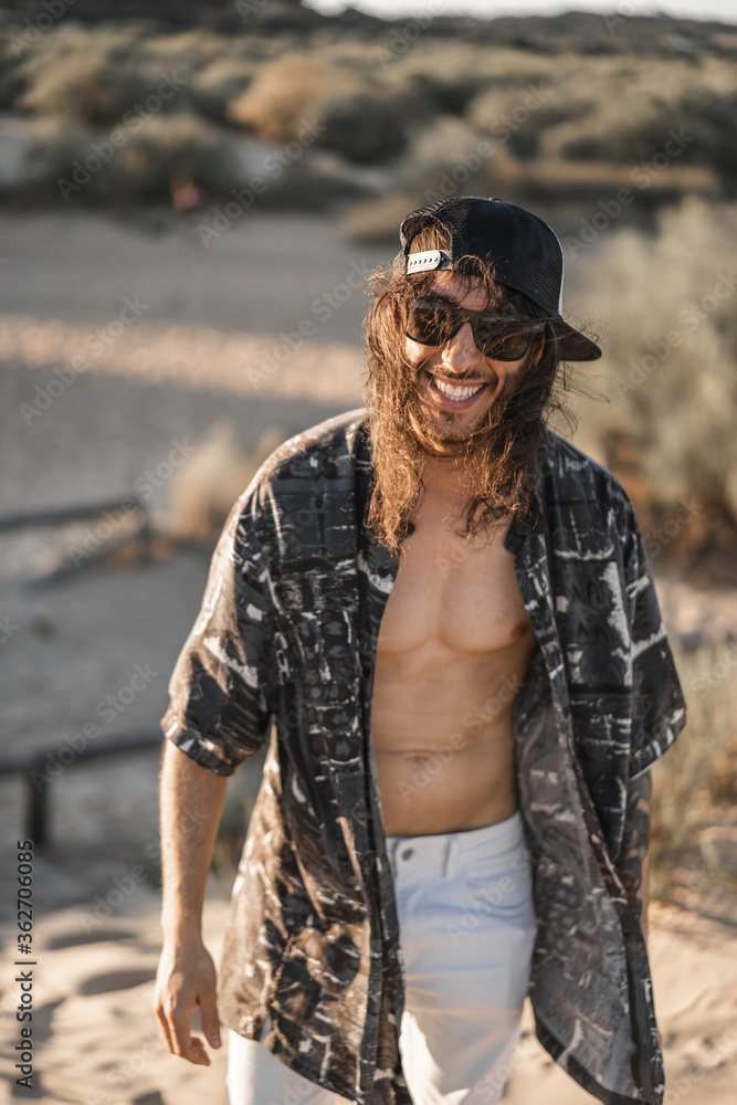Modelo de estilo surfero con pelo largo, gafas de sol y gorra, en unas ...