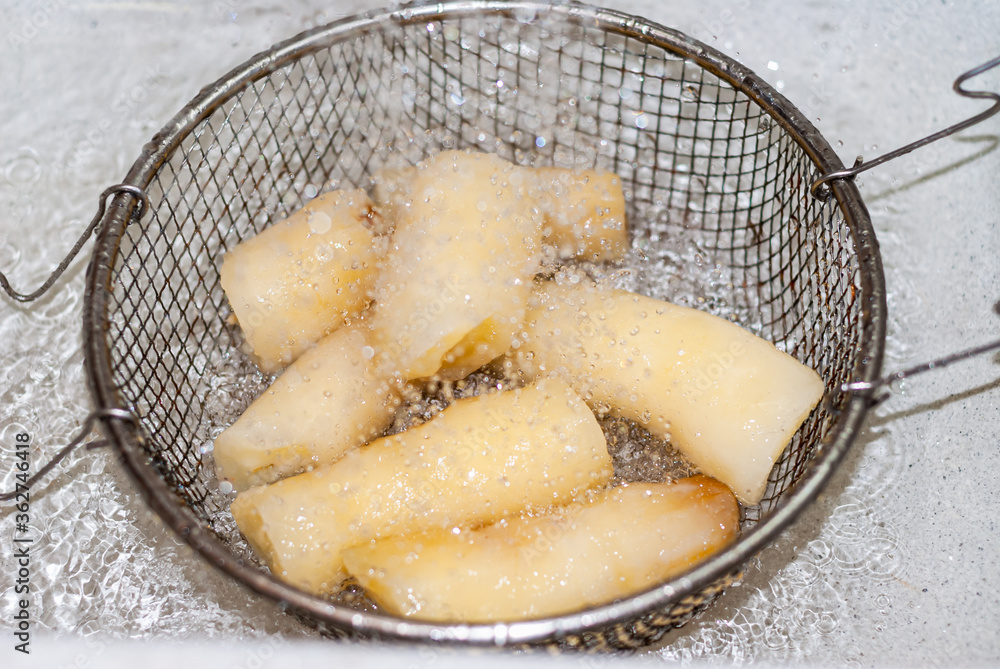 washing cassava with water in a metal strainer, Manihot esculenta ...