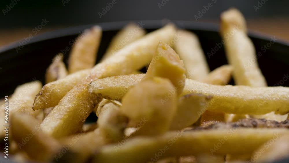 Fresh cut french fries being seasoned. Tossing and salting crispy fries ...