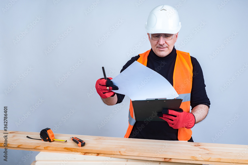Carpenter works with wood. Concept - a man looks through sketches on ...