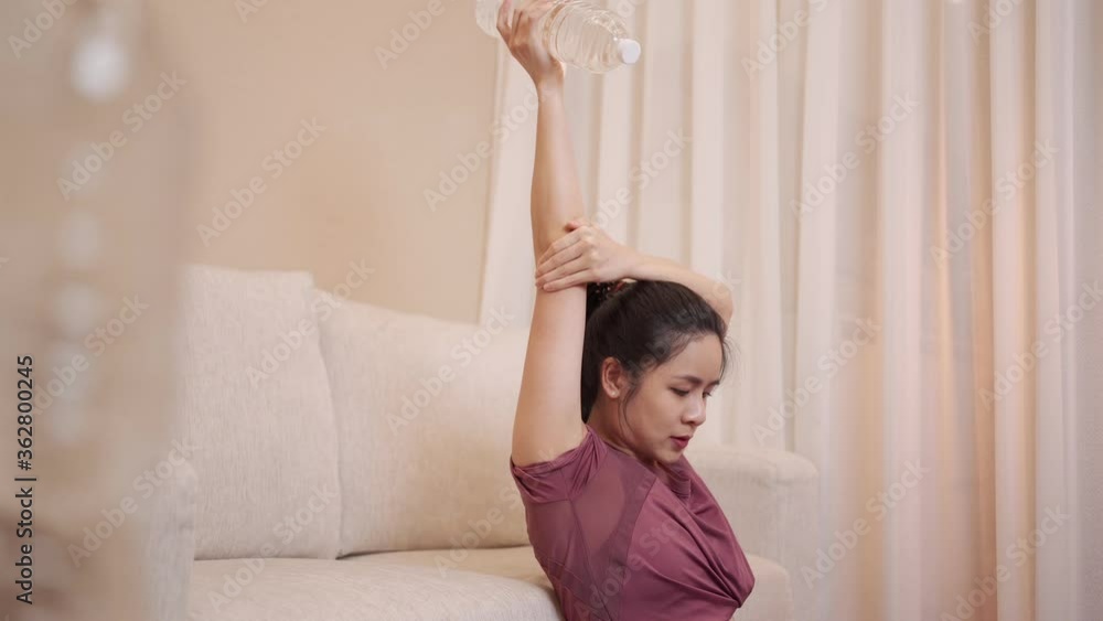 Stockvideon Asian young female sit down back against couch doing arm ...