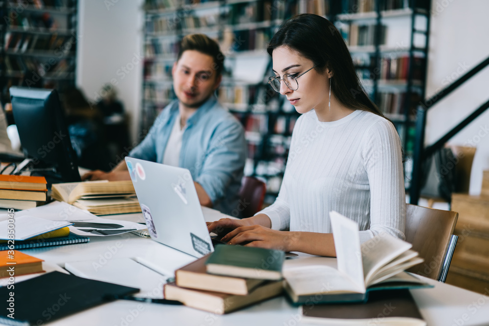 Concentrated female student typing on laptop computer creating report ...
