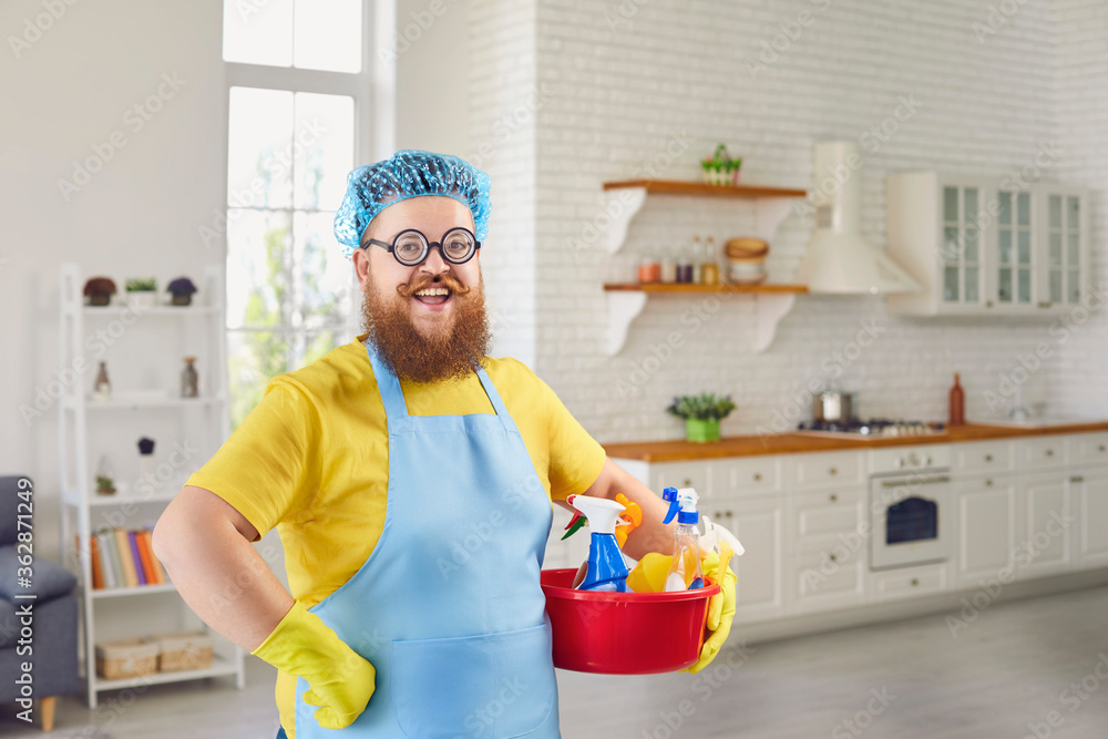 Funny fat man with a beard in an apron cleans the room in the house ...