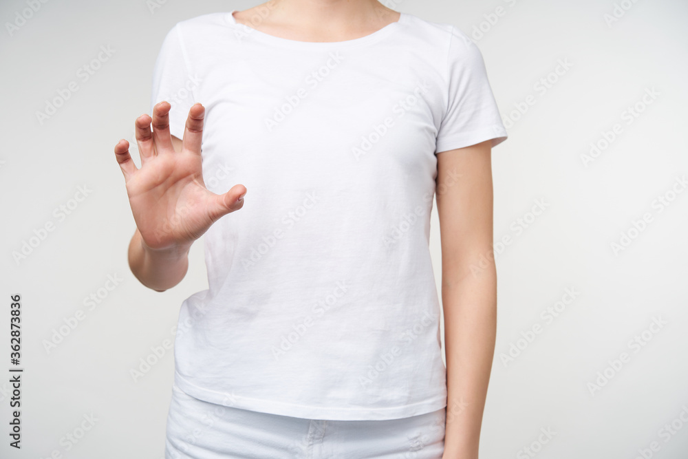 Studio photo of young female dressed in casual clothes keeping her hand ...