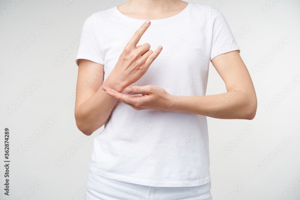 Indoor shot of young female keeping raised hands in front of herself ...