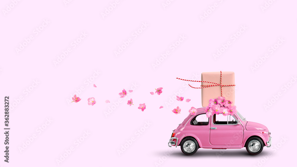 Pink car with gift box on a roof with flowers on pink background. Stock ...