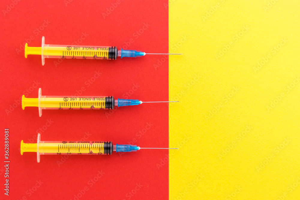 Disposable syringes on bright red-yellow background. Vaccination ...