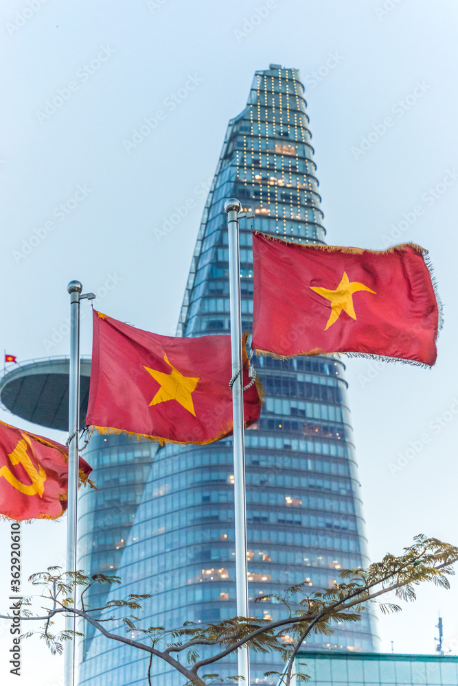 Bitexco tower under the blue sky next to a row of Vietnamese flags and ...