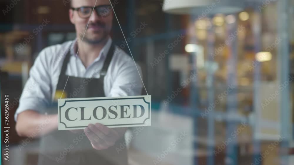 View through window of happy male cafe owner closing place for break ...