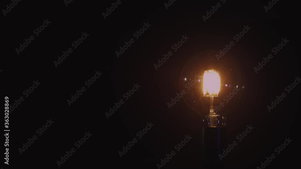 Vidéo Stock Incandescent light bulb isolated on black background. Glass ...