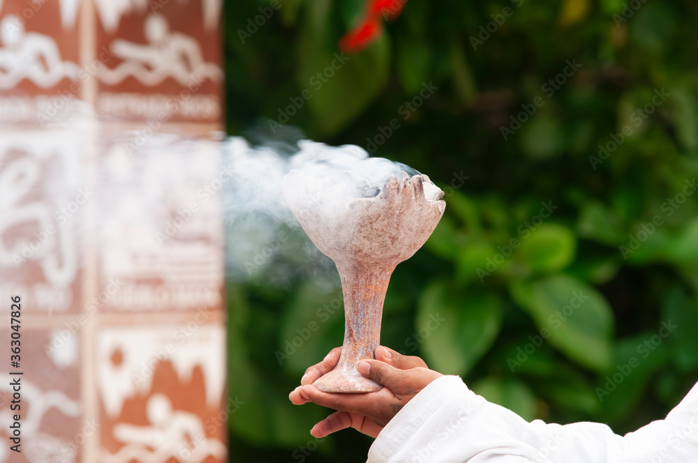 Young Mayan man holds in his hands a brazier lit with Copal smoke ...