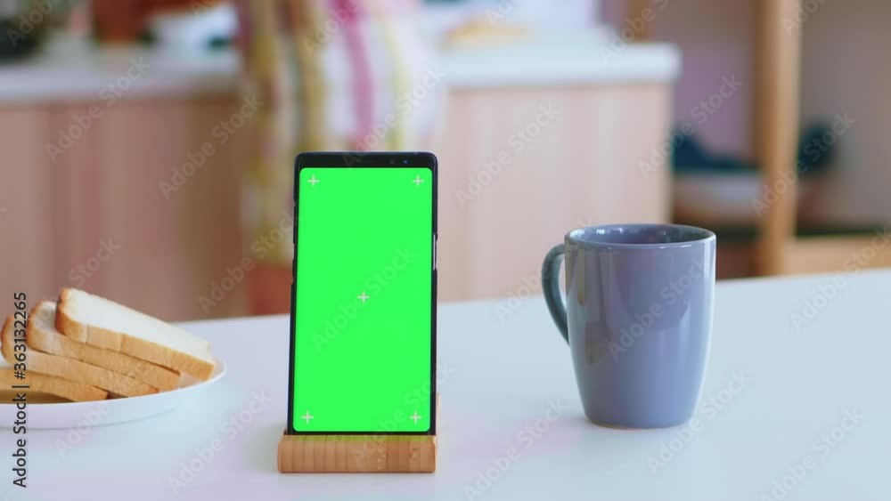 Green mockup on smartphone in kitchen. Housewife baked tasty croissants ...