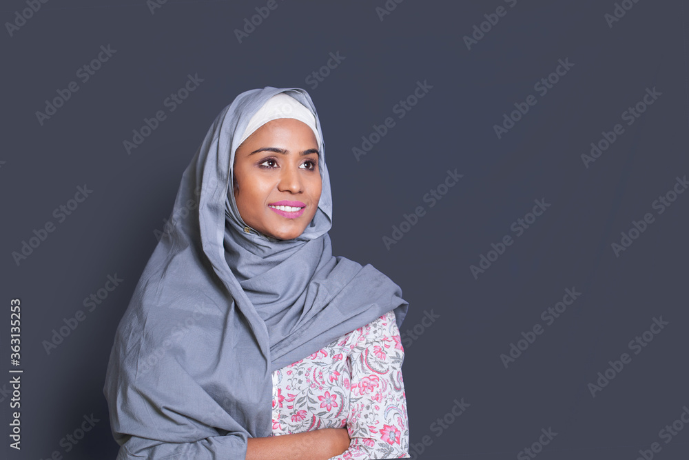 Beautiful muslim Indian young woman wearing hijab standing over grey ...