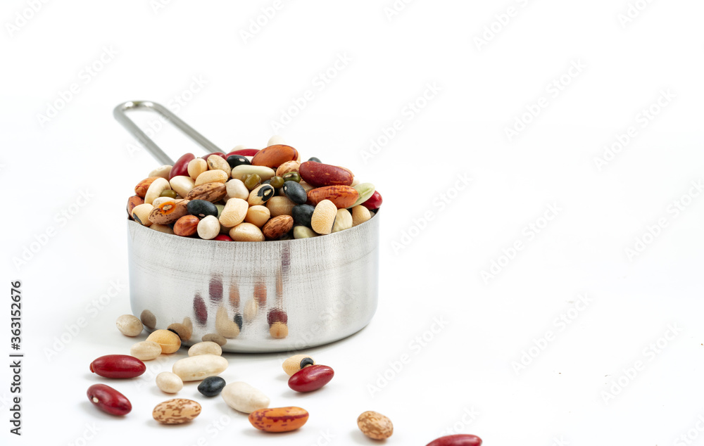 Varieties of beans in stainless steel measuring cup on white background ...
