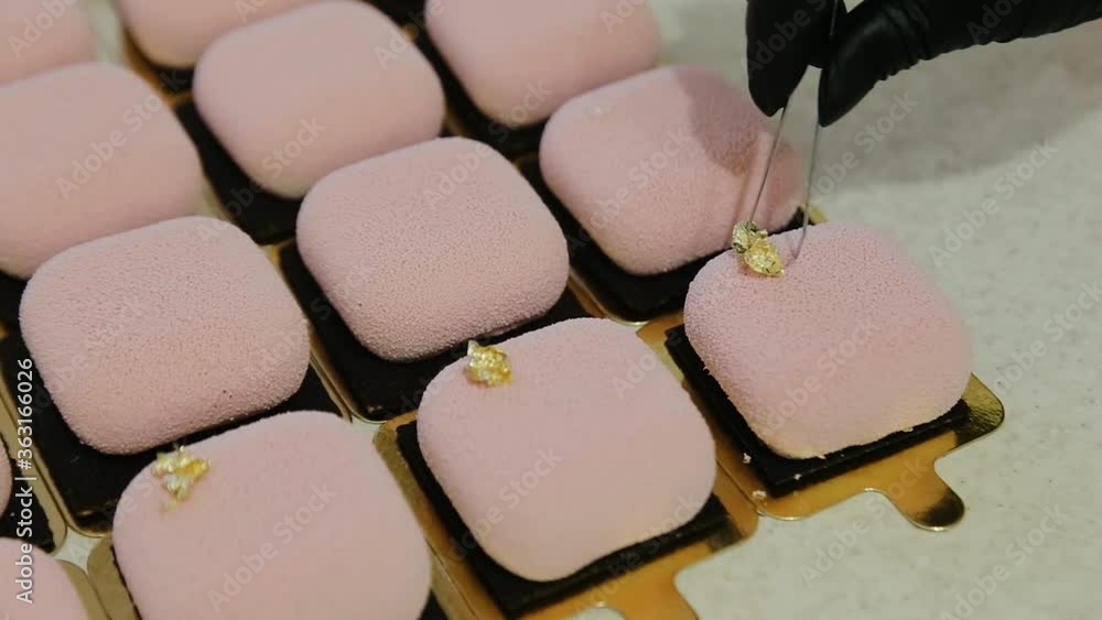 Confectioner adding an edible gold colored foil decor element to the ...