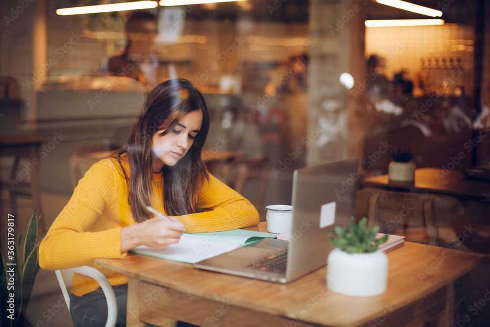 Attractive modern student making notes on technology concept in ...