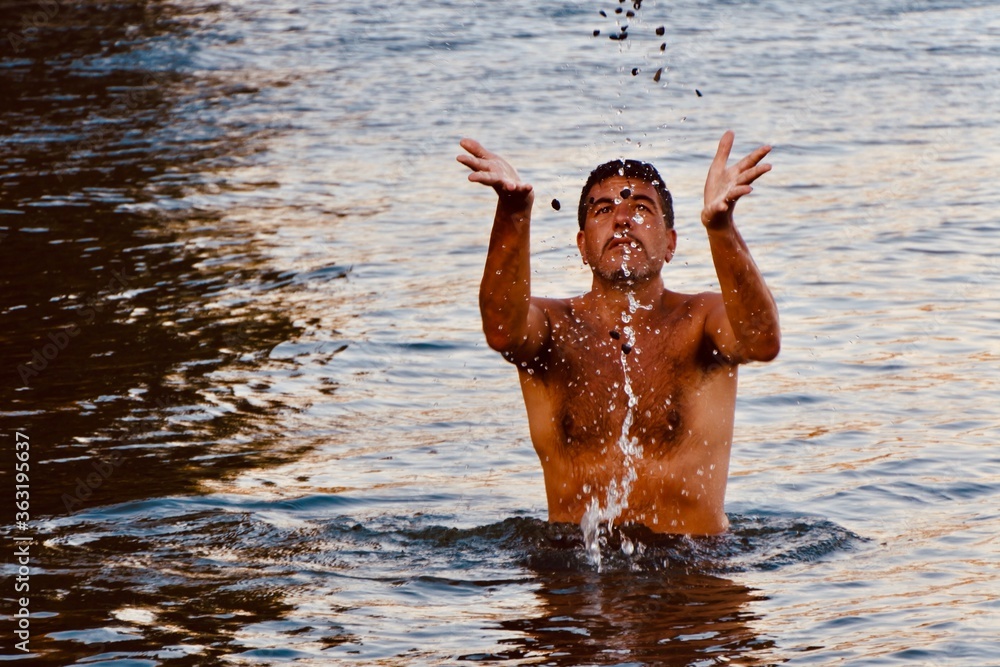 Shirtless Man Throwing Pebbles In Water Stock Photo | Adobe Stock
