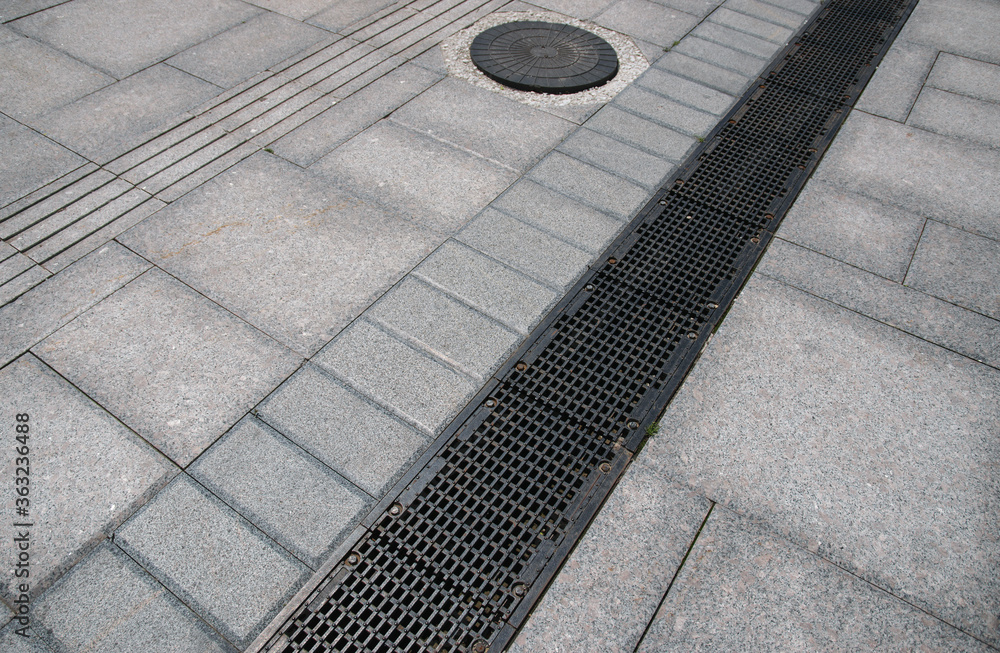 Water drain on the road to collect raining water. Stock Photo | Adobe Stock