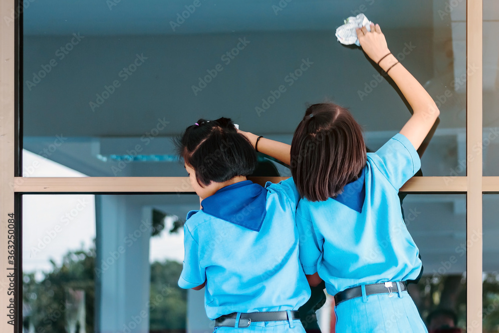 Back view of female students are helping to wipe the glass with wet ...