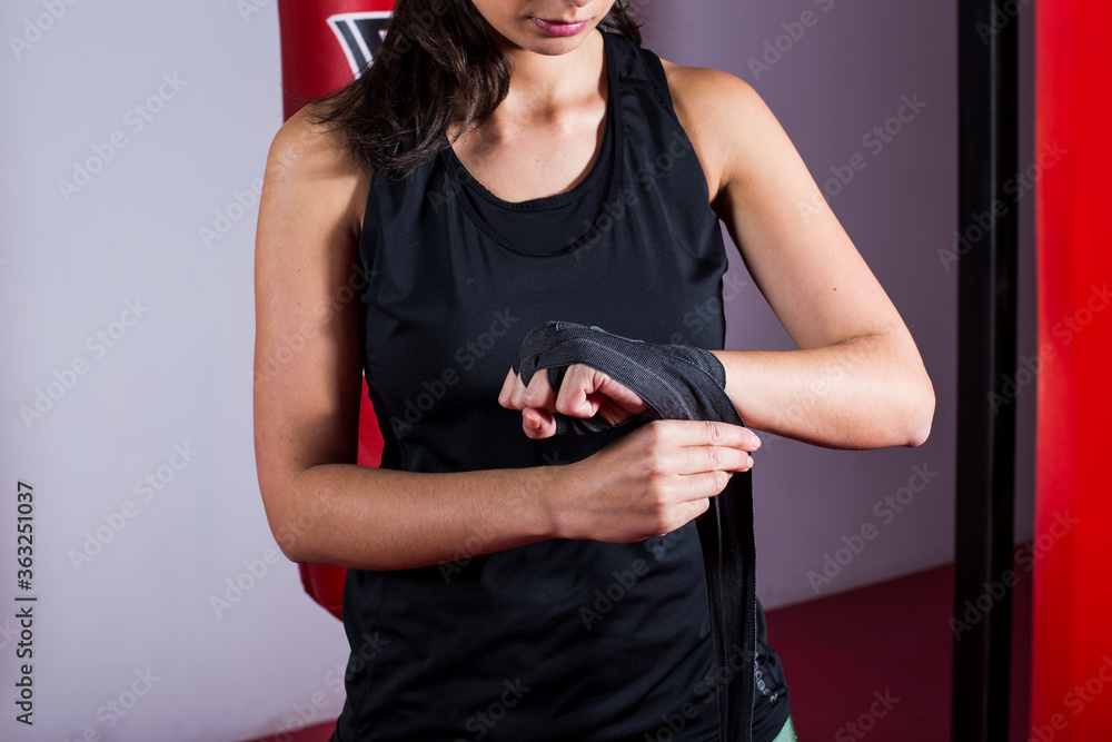 Boxing woman fighter wrapping the bandage on her hands, before training ...
