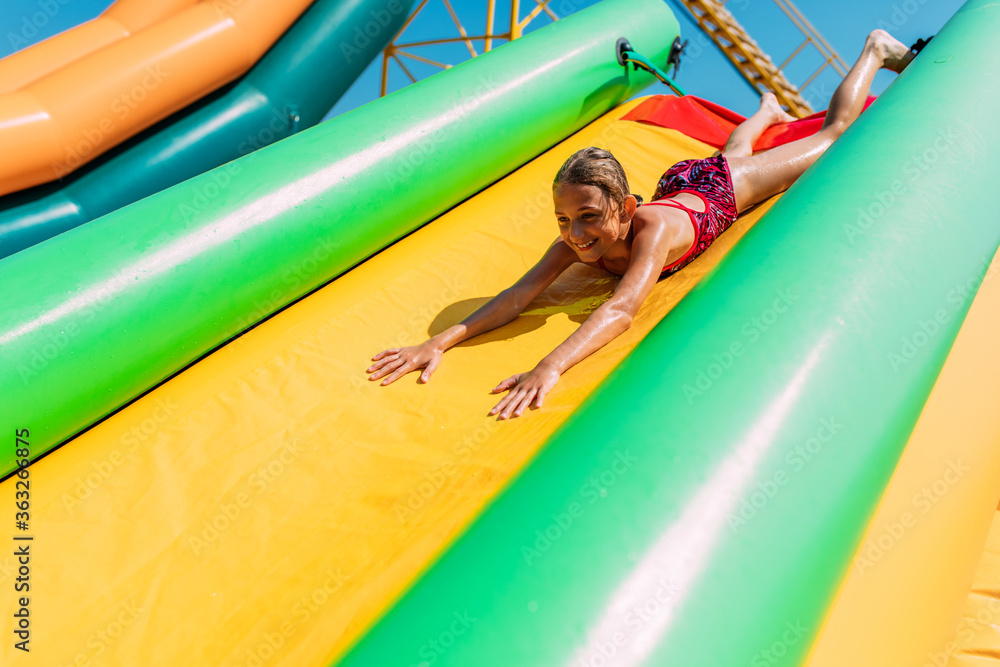 Happy little girl rides a water inflatable slide in a water Park ...