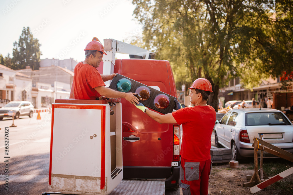A middle-aged caucasian worker in a red uniform and helmet passes a ...
