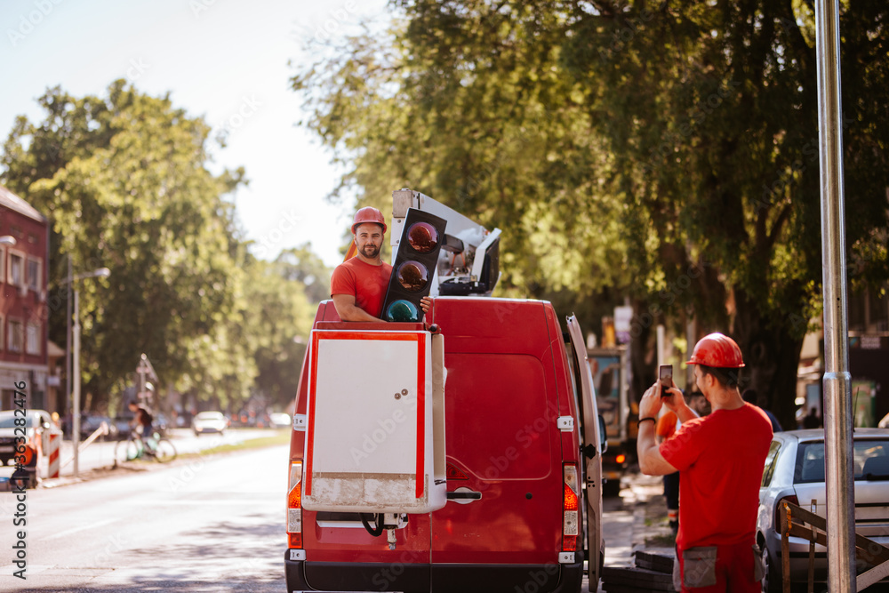 A caucasian worker in a red T-shirt stands in a basket in a crane with ...