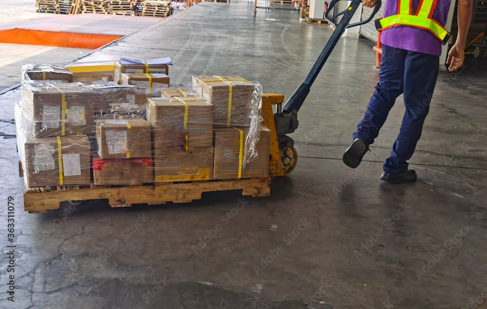 Worker loading and unloading shipment carton boxes and goods on wooden ...
