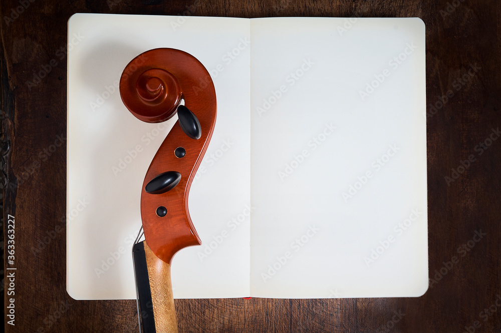 violin head in side view on white paper notepad and wooden background ...