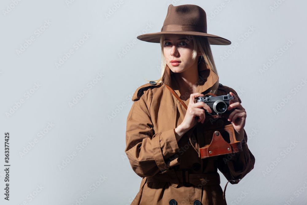 Woman in hat and cloak as a spy with camera on gray background. Stock ...