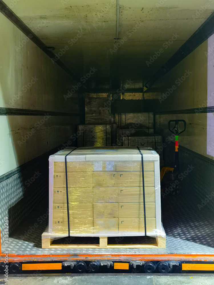 Worker loading and unloading shipment carton boxes and goods on wooden ...