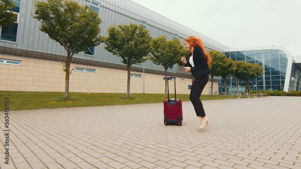 Happy young woman dancing near luggage suitcase on airport terminal ...