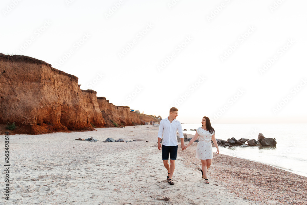 Loving couple in white clothes during a honeymoon at sea walk on the ...