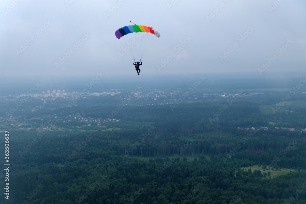 Skydiving. A rainbow colored parachute flies in the sky Stock Photo ...
