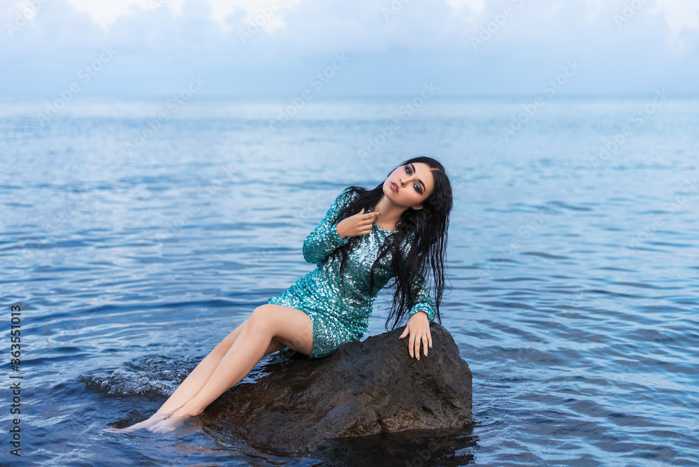 Young beautiful woman relaxing on the big stone. Girl in a little green ...