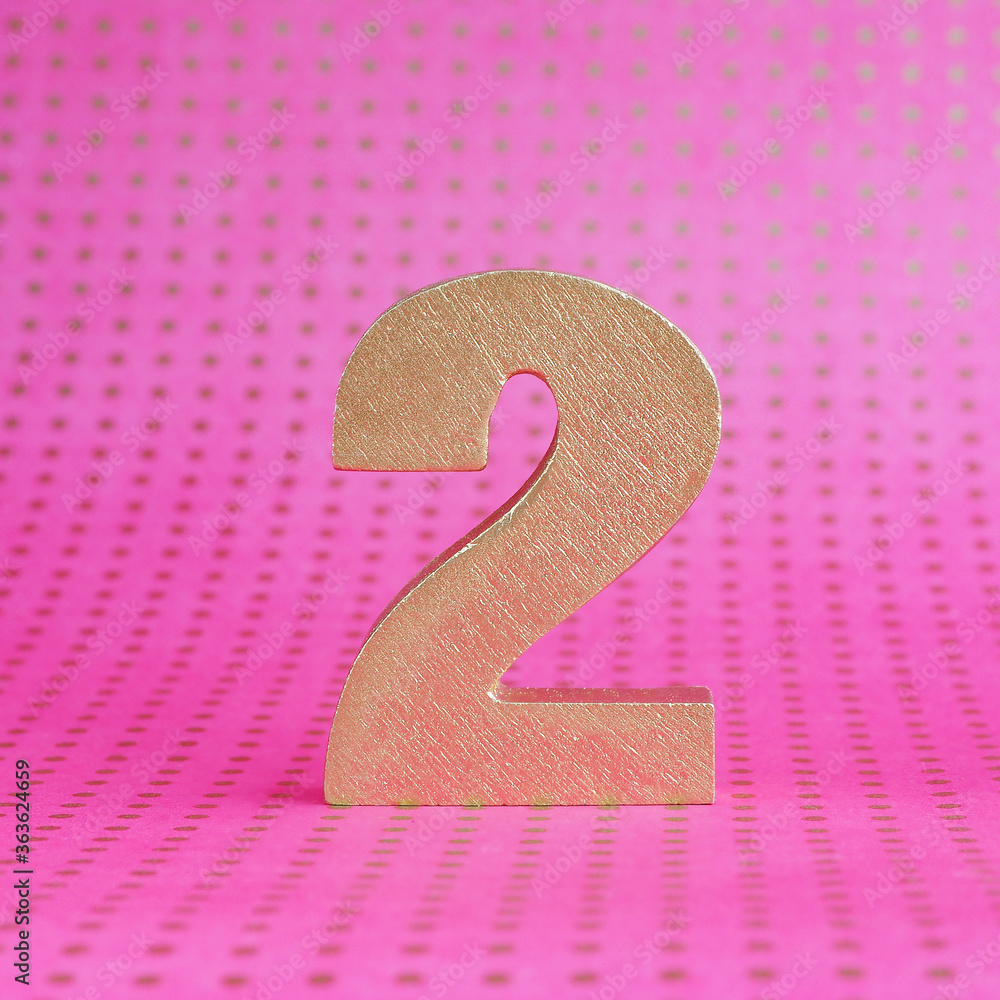 Golden volumetric number 2 on a bright pink polka dot background. copy ...
