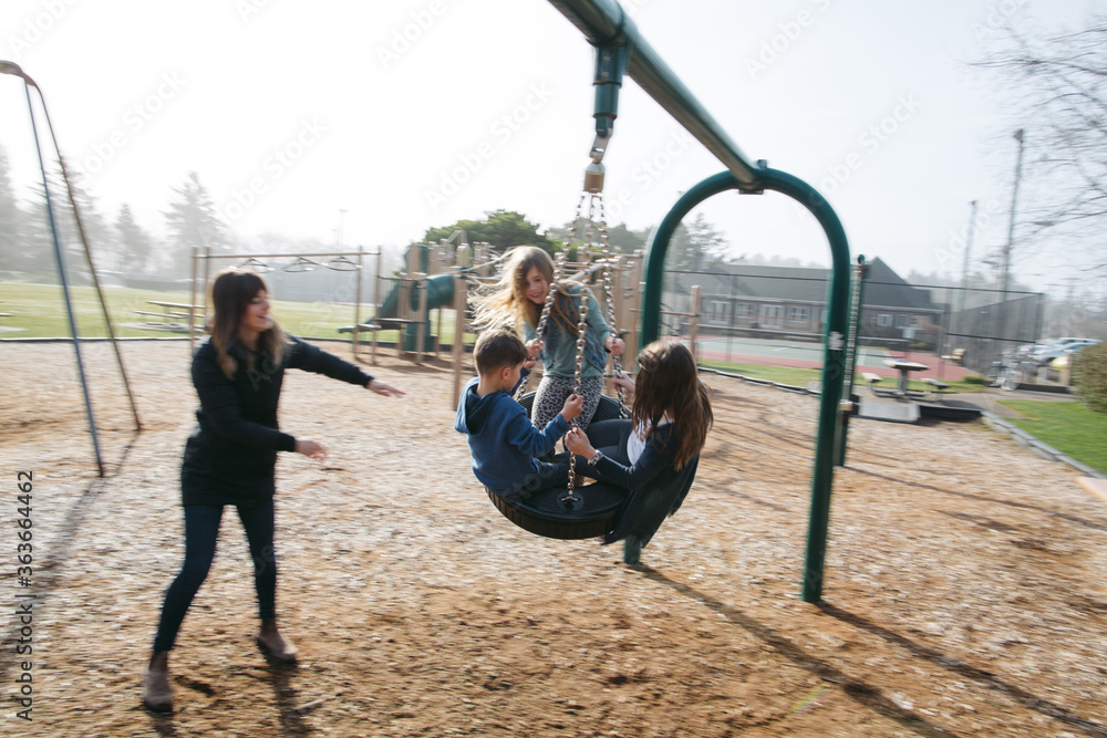 Mom pushing kids on tire swing at local playground. Stock Photo | Adobe ...