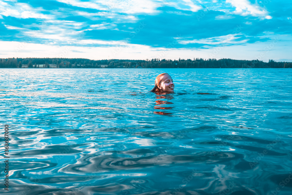 Finnish girl swimming in the lake during warm scandinavian midsummer ...