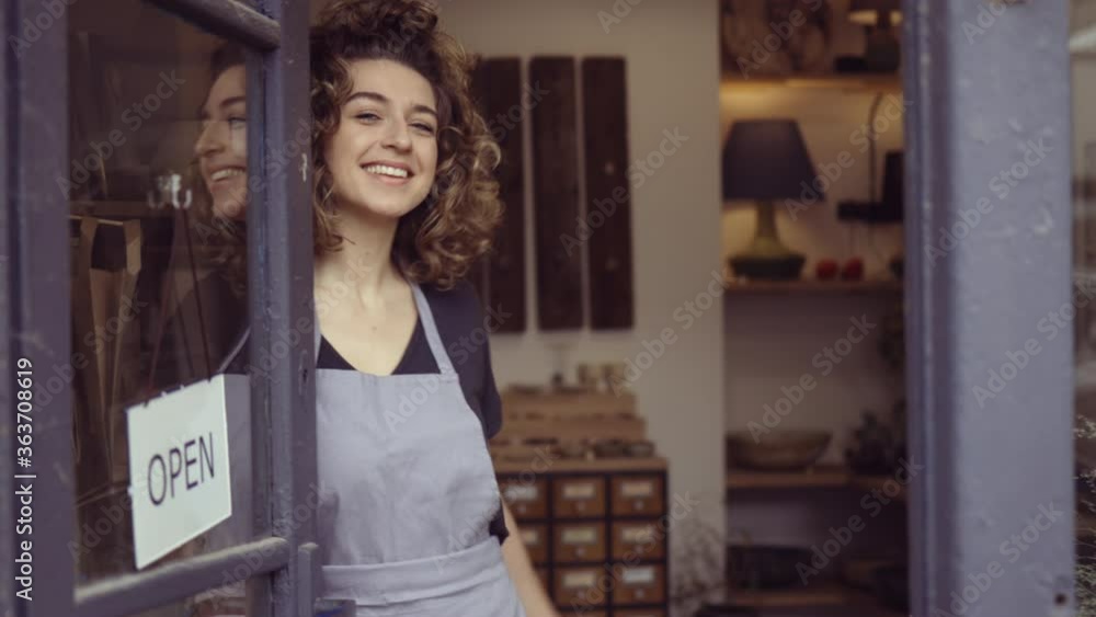 Smiling young woman at the door of her shop welcoming customers Stock ...