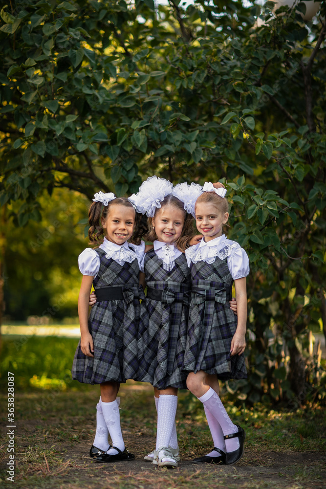 Three girls in school uniform with tails and white bows posing at the ...